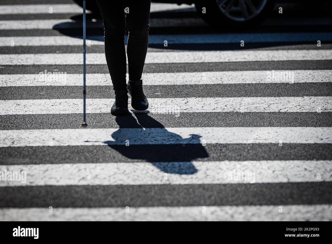 Blind woman walking on city streets, using her white cane to navigate ...