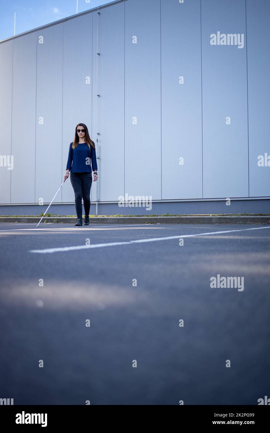 Young woman with impaired vision walking on city streets, using her ...