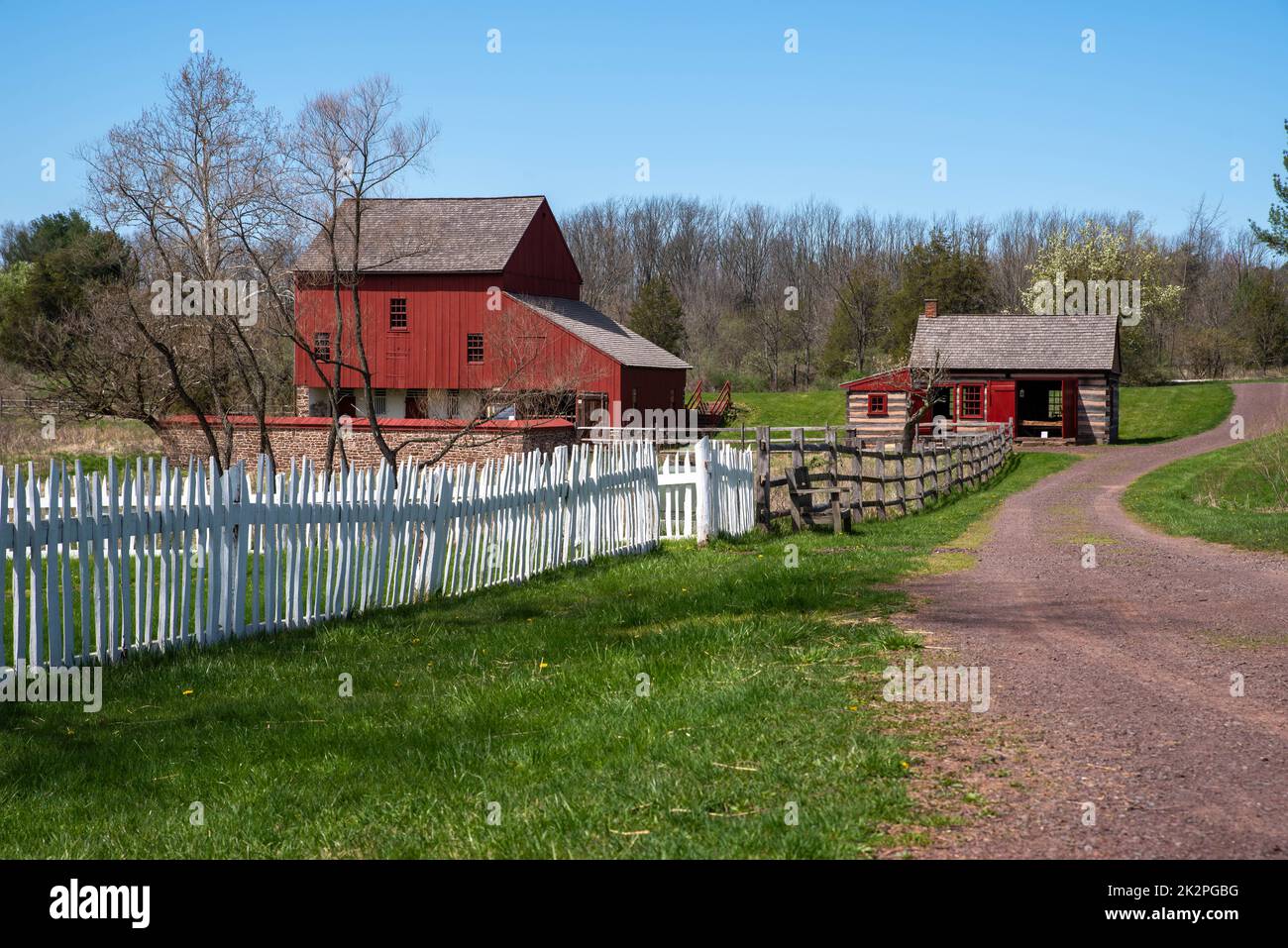 Dirt road with picket fence and a colonial American red barn and log ...