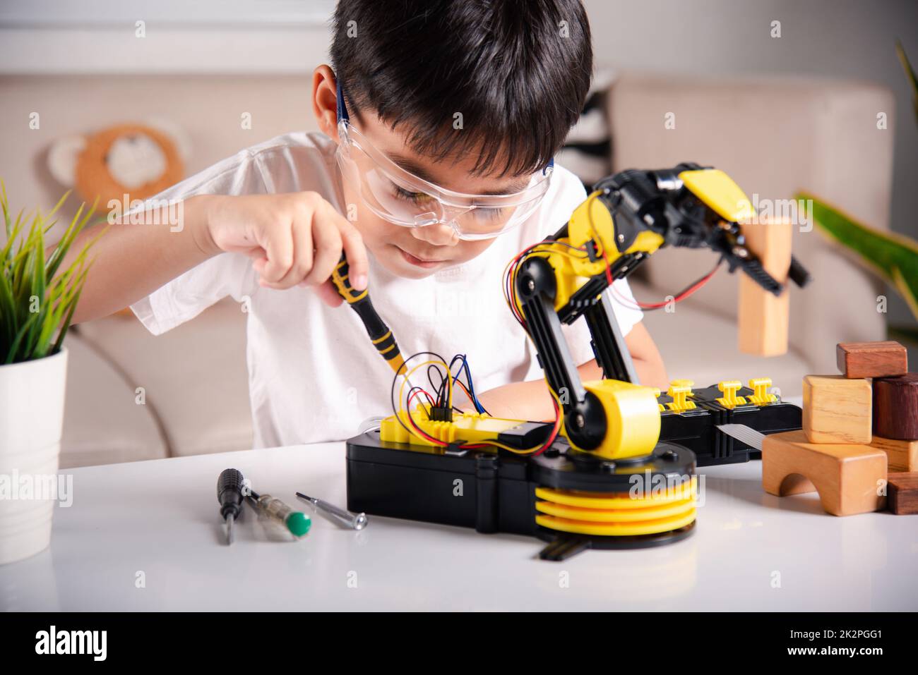 Happy Asian little kid boy using screwdriver to fixes screws robotic ...