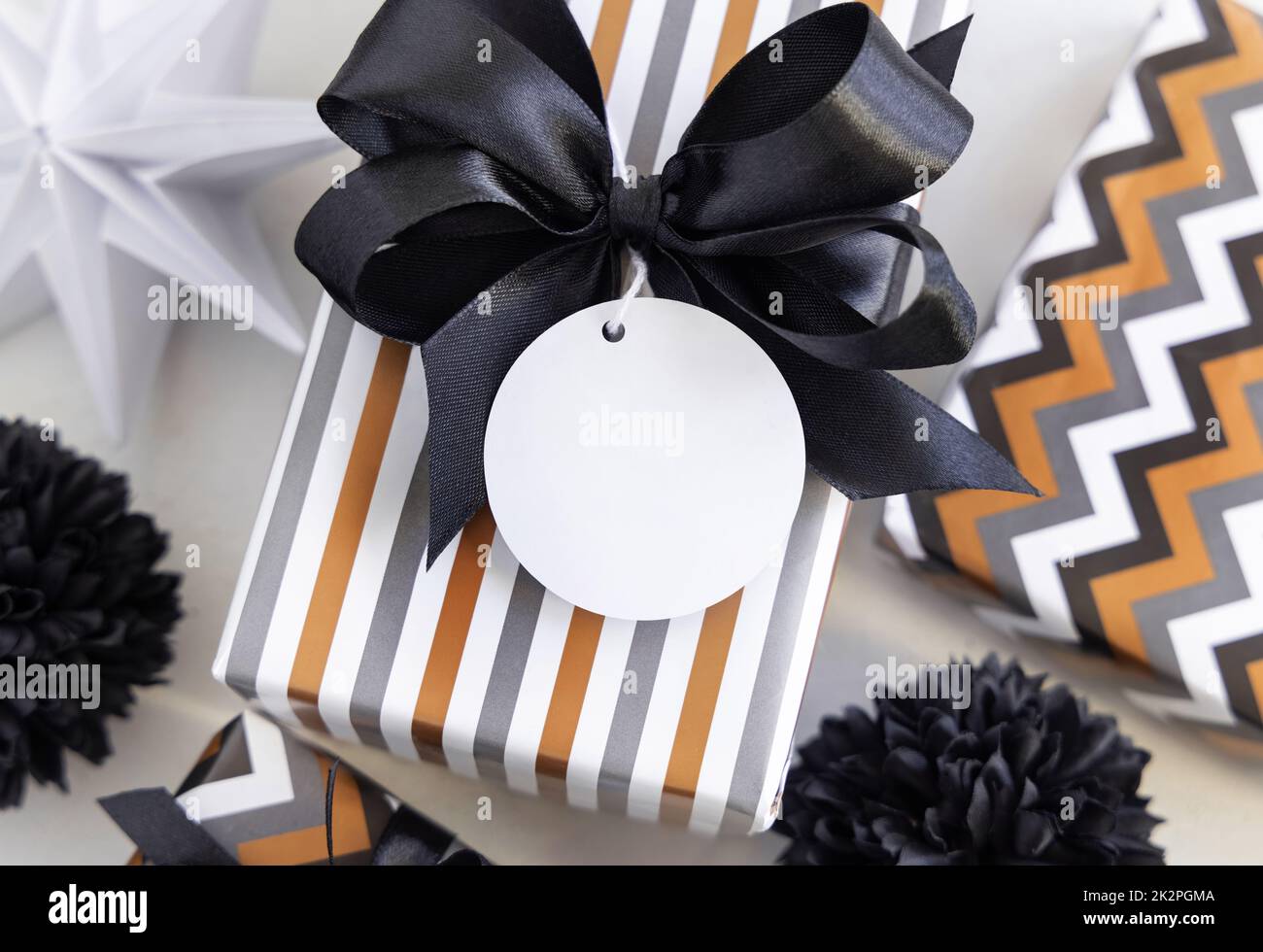 Wrapped present with round blank gift tag and black bow close up, label ...