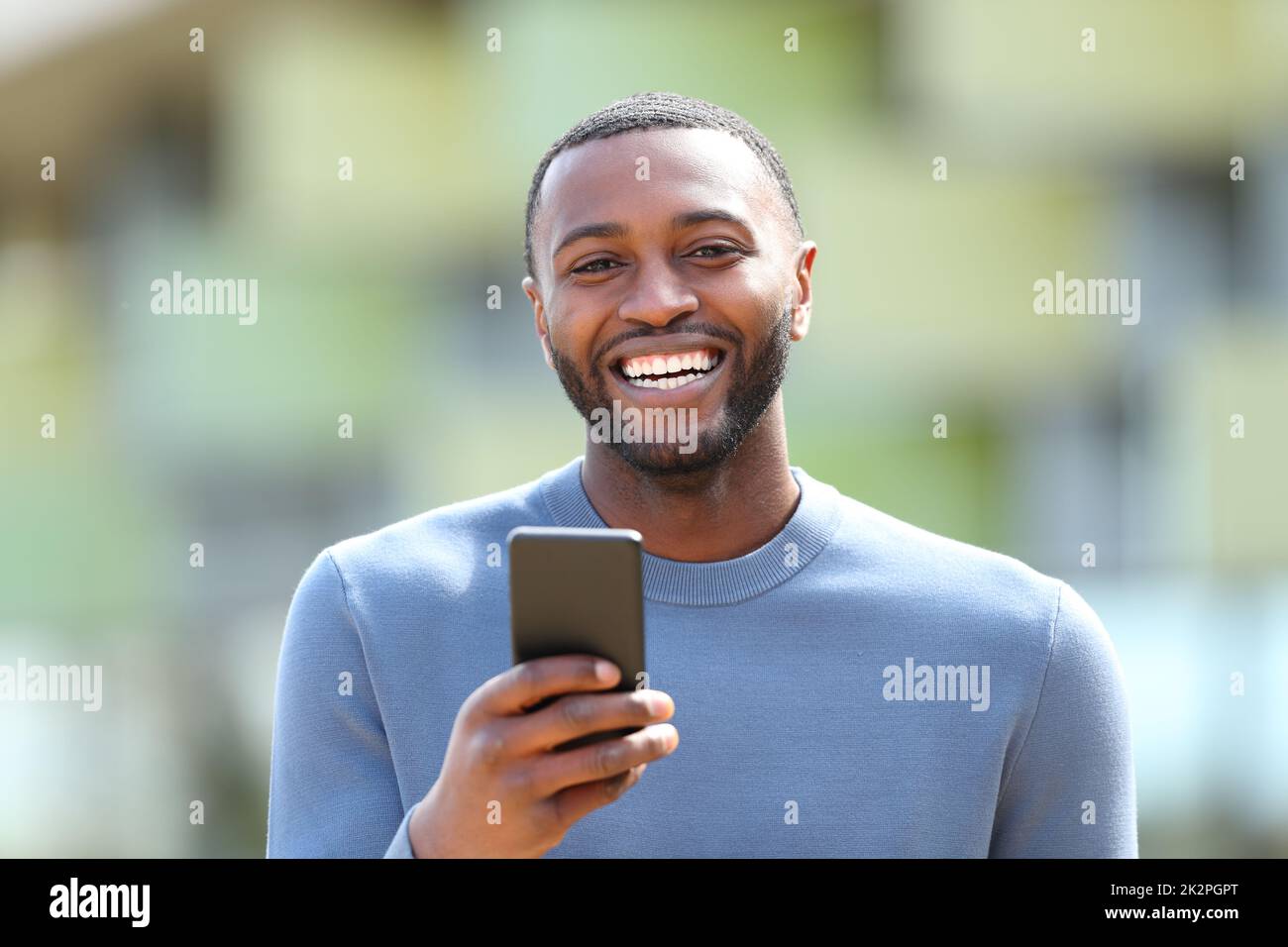 Happy man with black skin laughing holding phone looking at you Stock ...