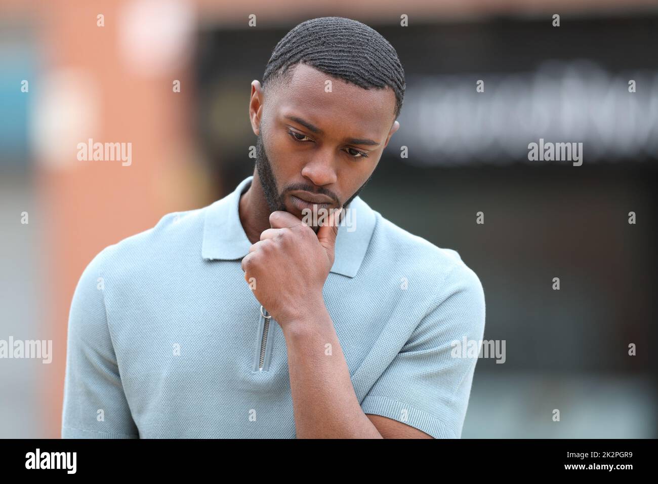 Pensive man with black skin walking alone in the street Stock Photo - Alamy