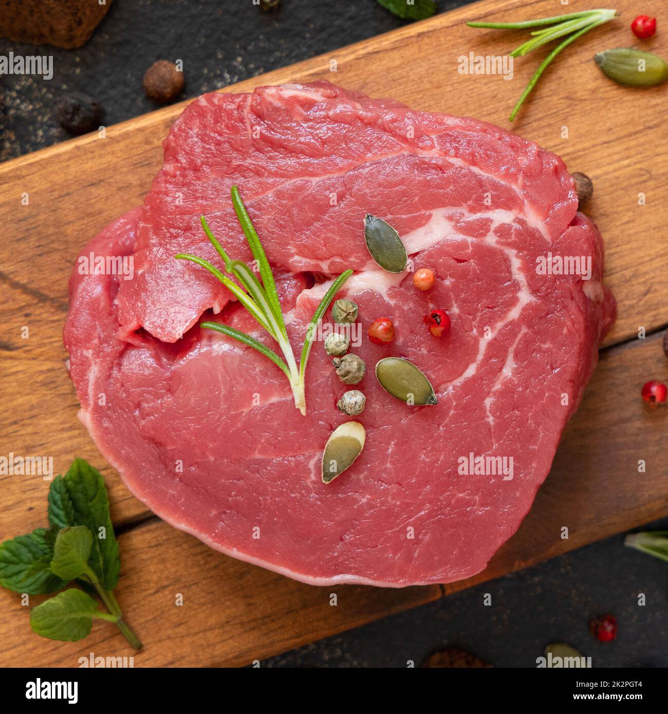 Raw beef fillet steak with herbs and spices on wooden board on dark ...