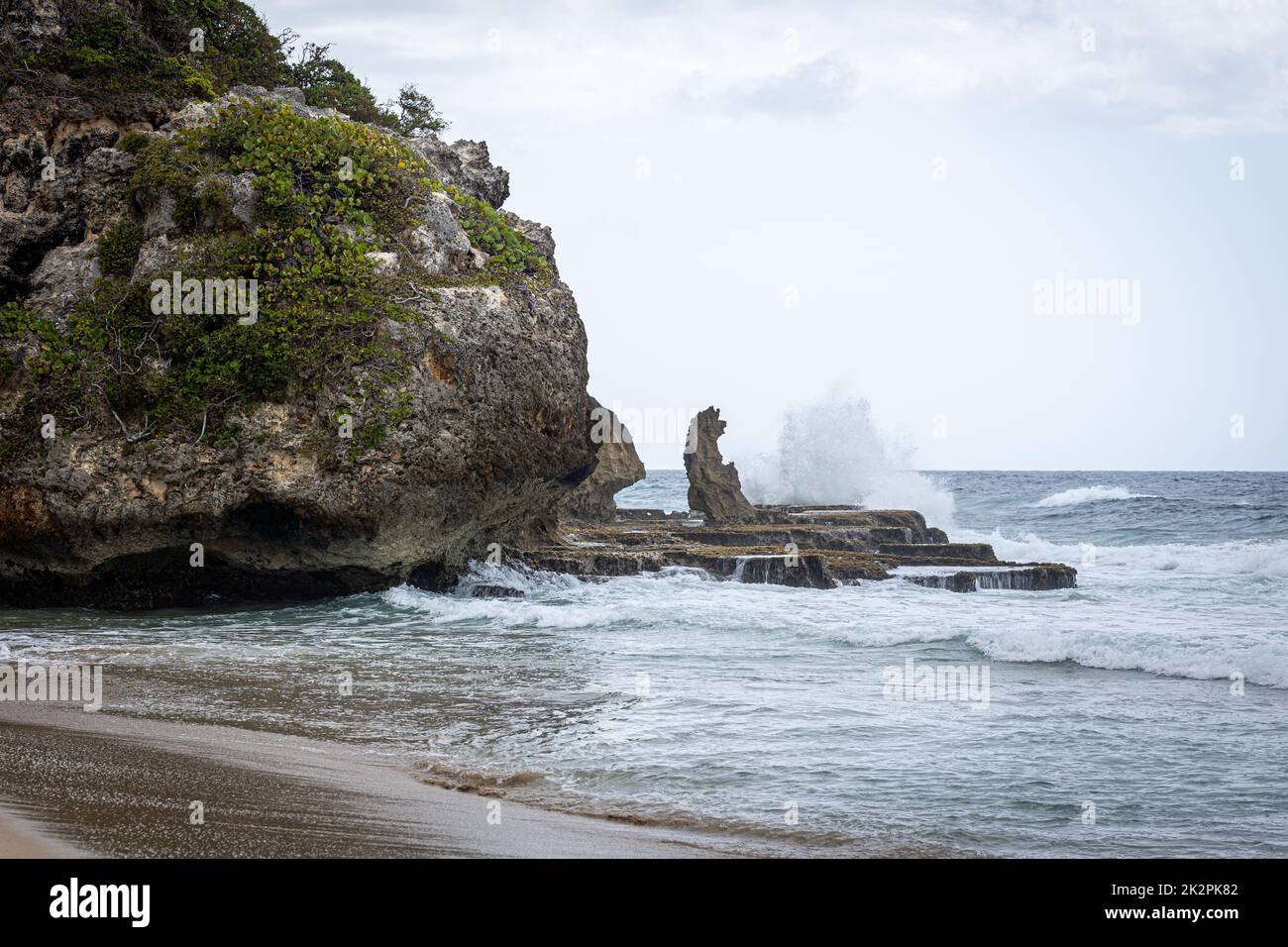 The sea waves crashing into steep rock formations on the beach in ...