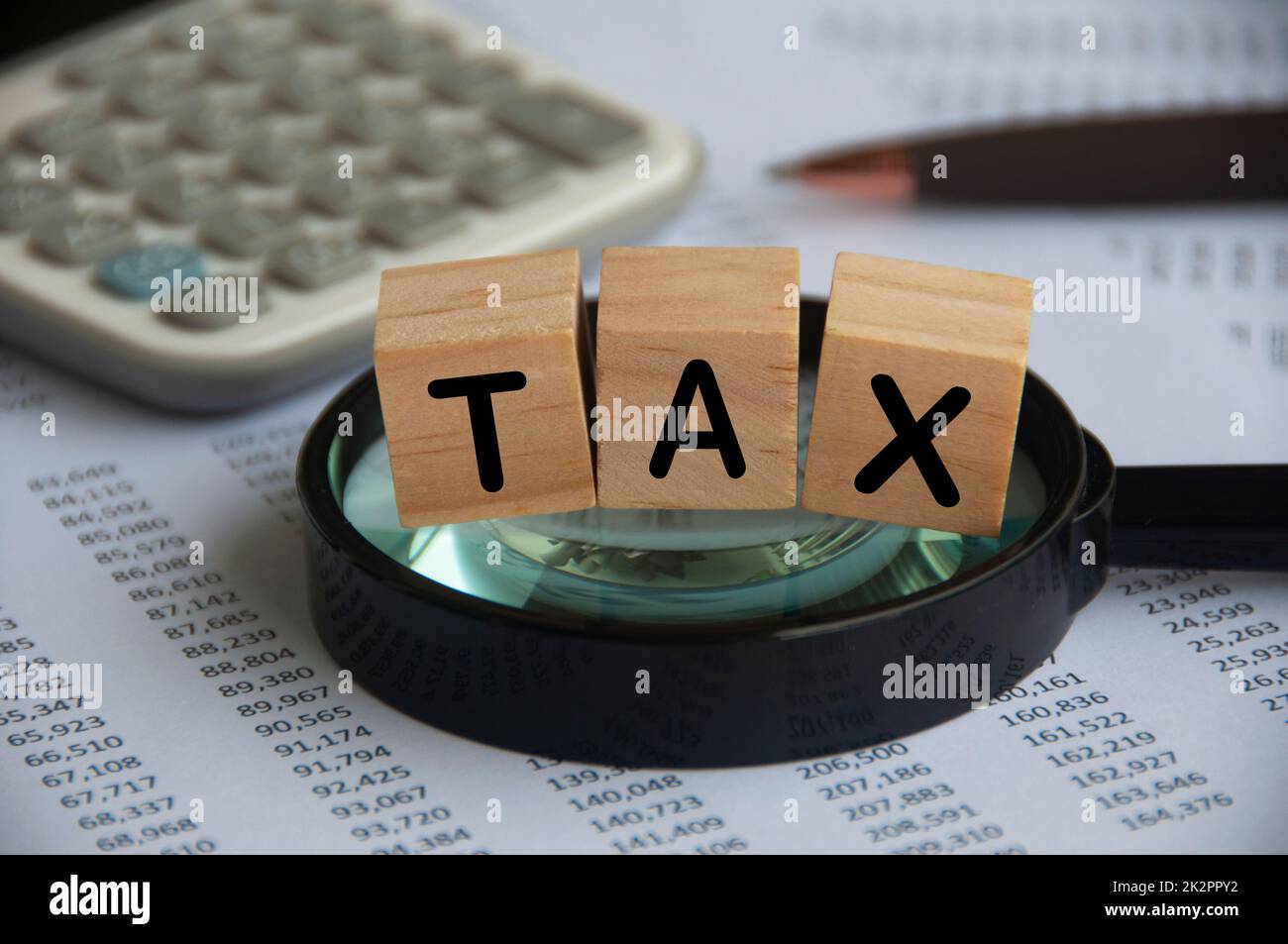 Tax word labeled wooden blocks on magnifying glass. Tax investigation ...