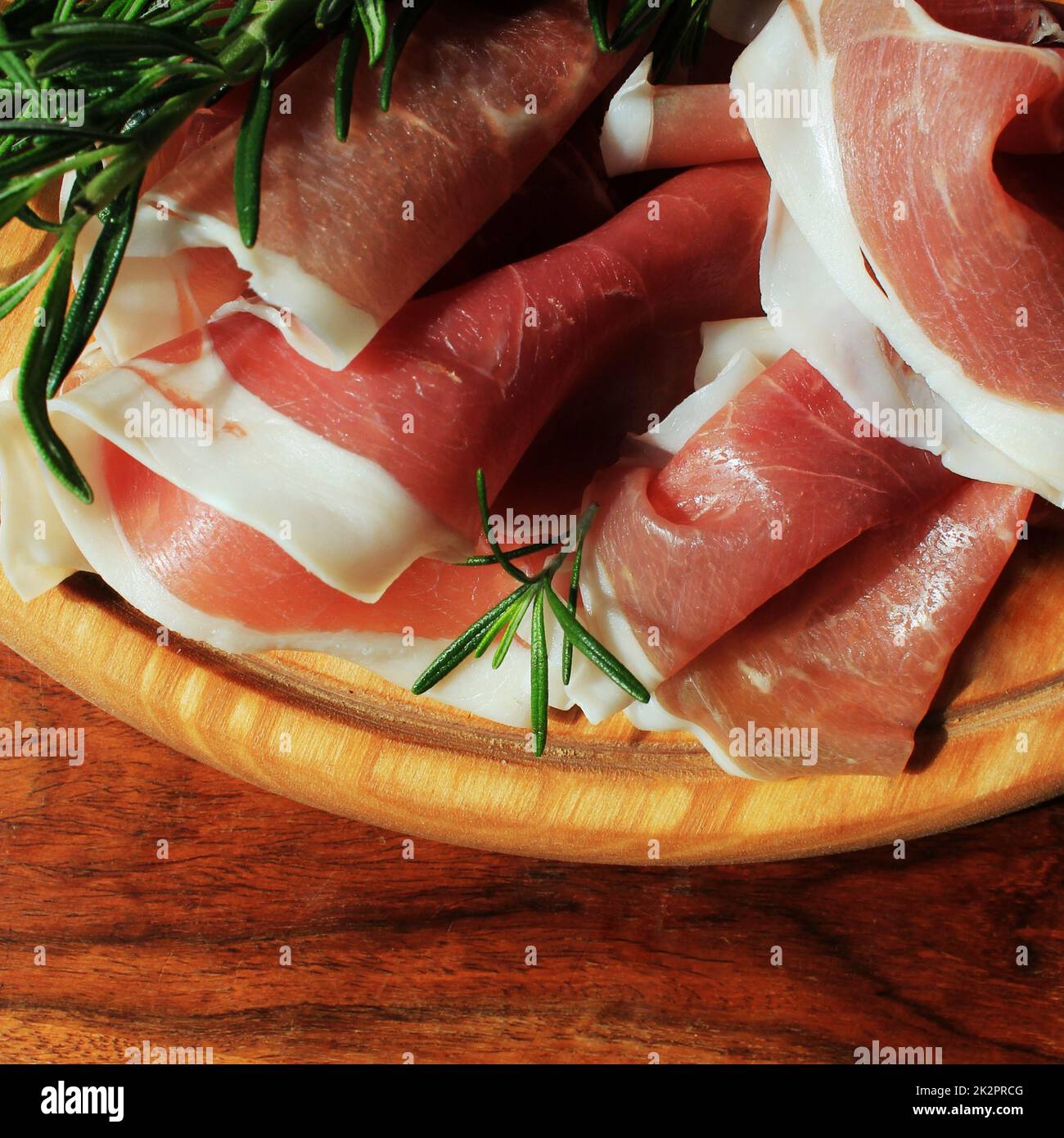 Italian prosciutto crudo or jamon with rosemary on cutting board Stock ...