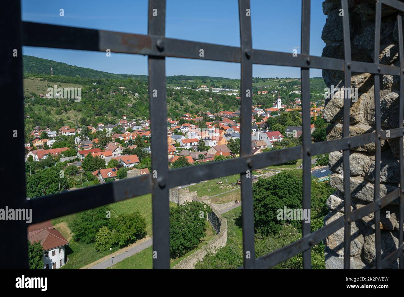The view of a town in green forest behind the old fenced gate of the ...