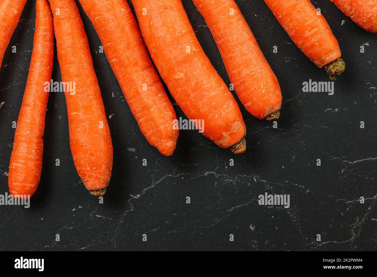 Tabletop view, raw carrot on black stone board Stock Photo - Alamy