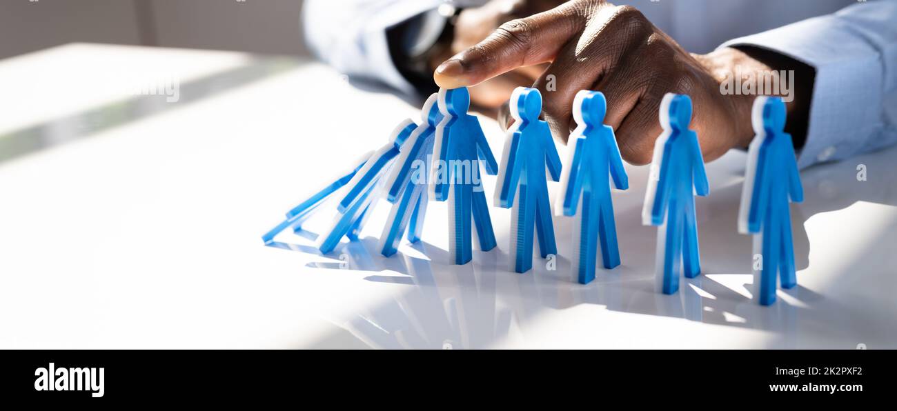 Businessperson Stopping Falling Persons On Desk Stock Photo - Alamy