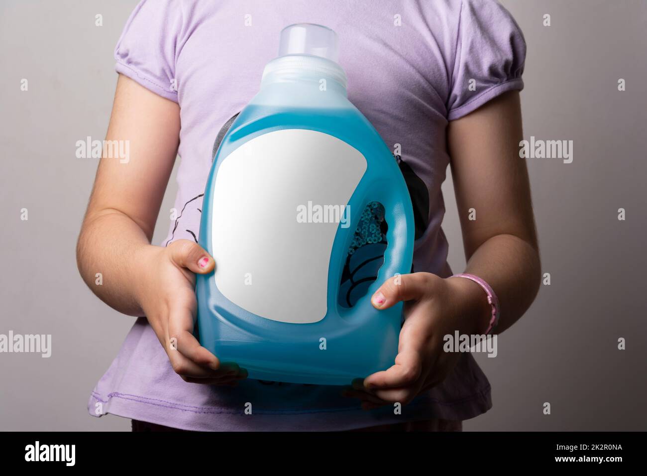 Little girl holding a cloth detergent liquid bottle at hand mock-up ...