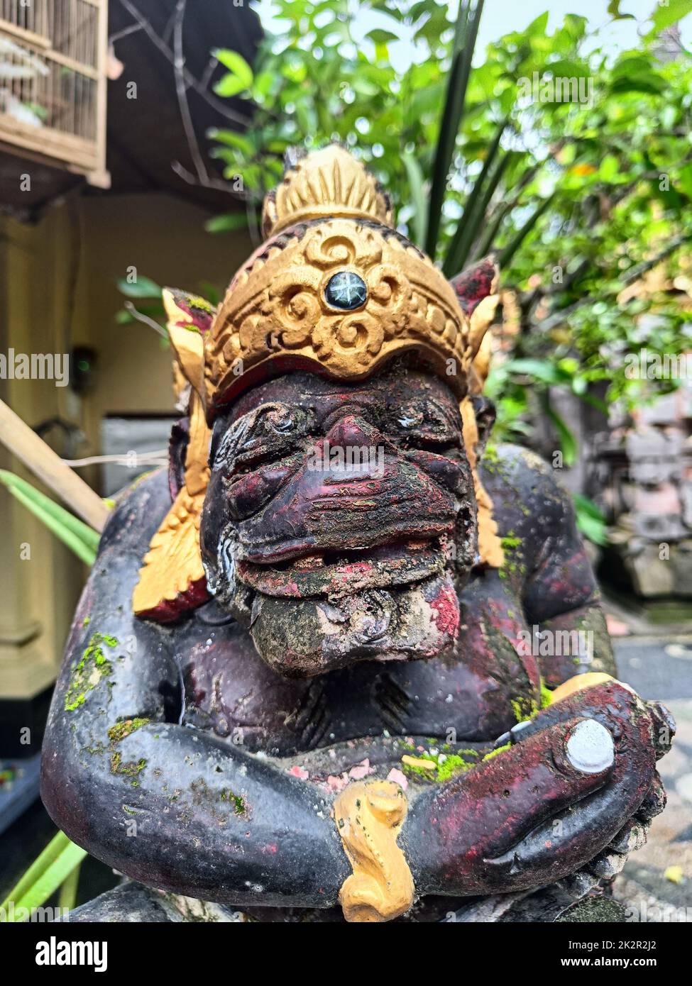 The vertical close-up view of the Balinese statue with golden ...