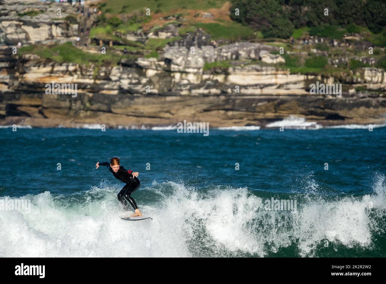 A surfer standing on the shortboard and catching waves, scattering ...