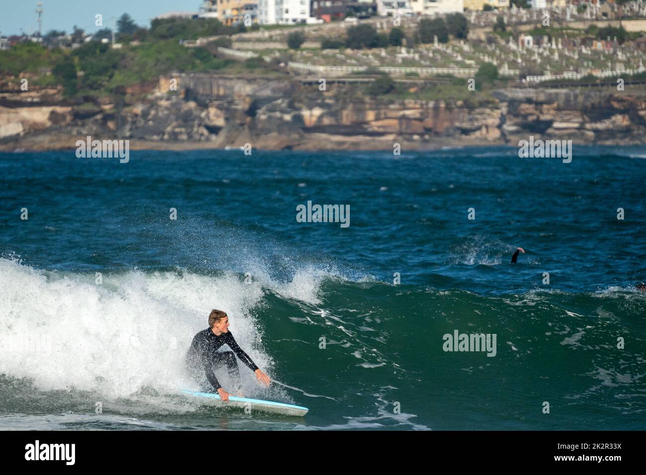 A surfer at the beach stuck up on the shortboard and scattering water ...