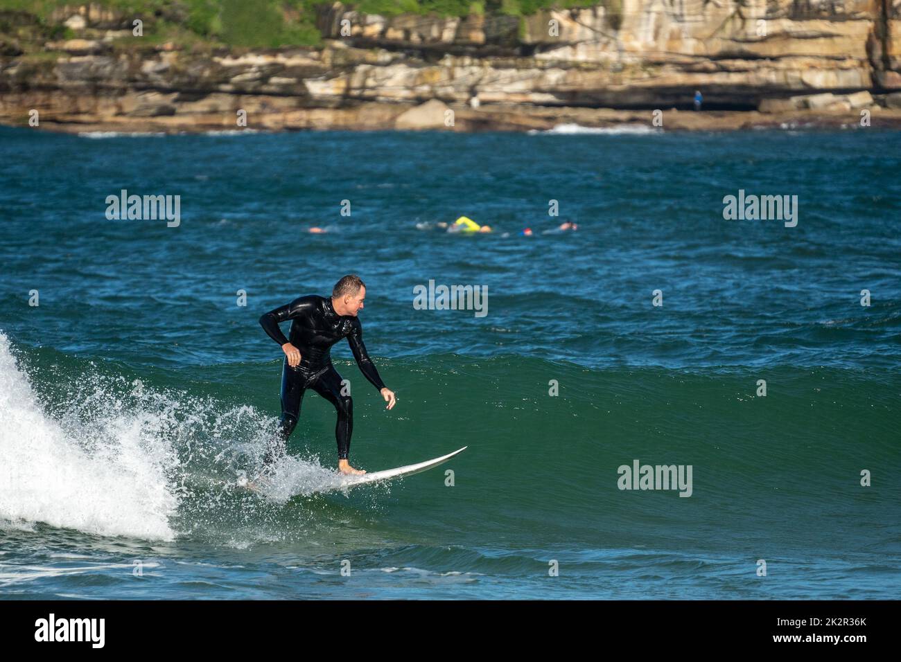 A surfer standing on the shortboard and catching waves, scattering ...