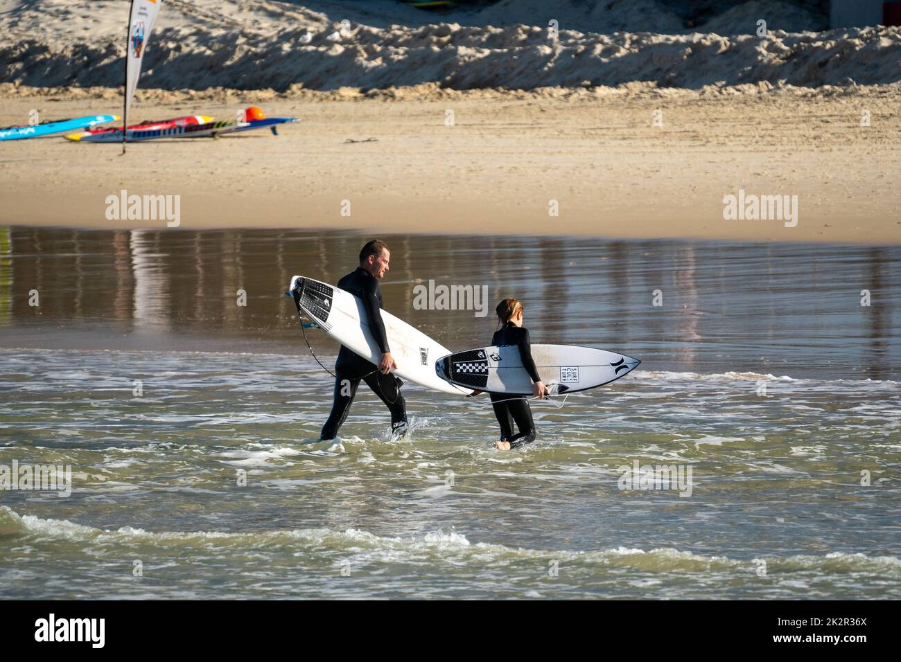 A rear shot of surfers holding shortboards and going back to the beach ...