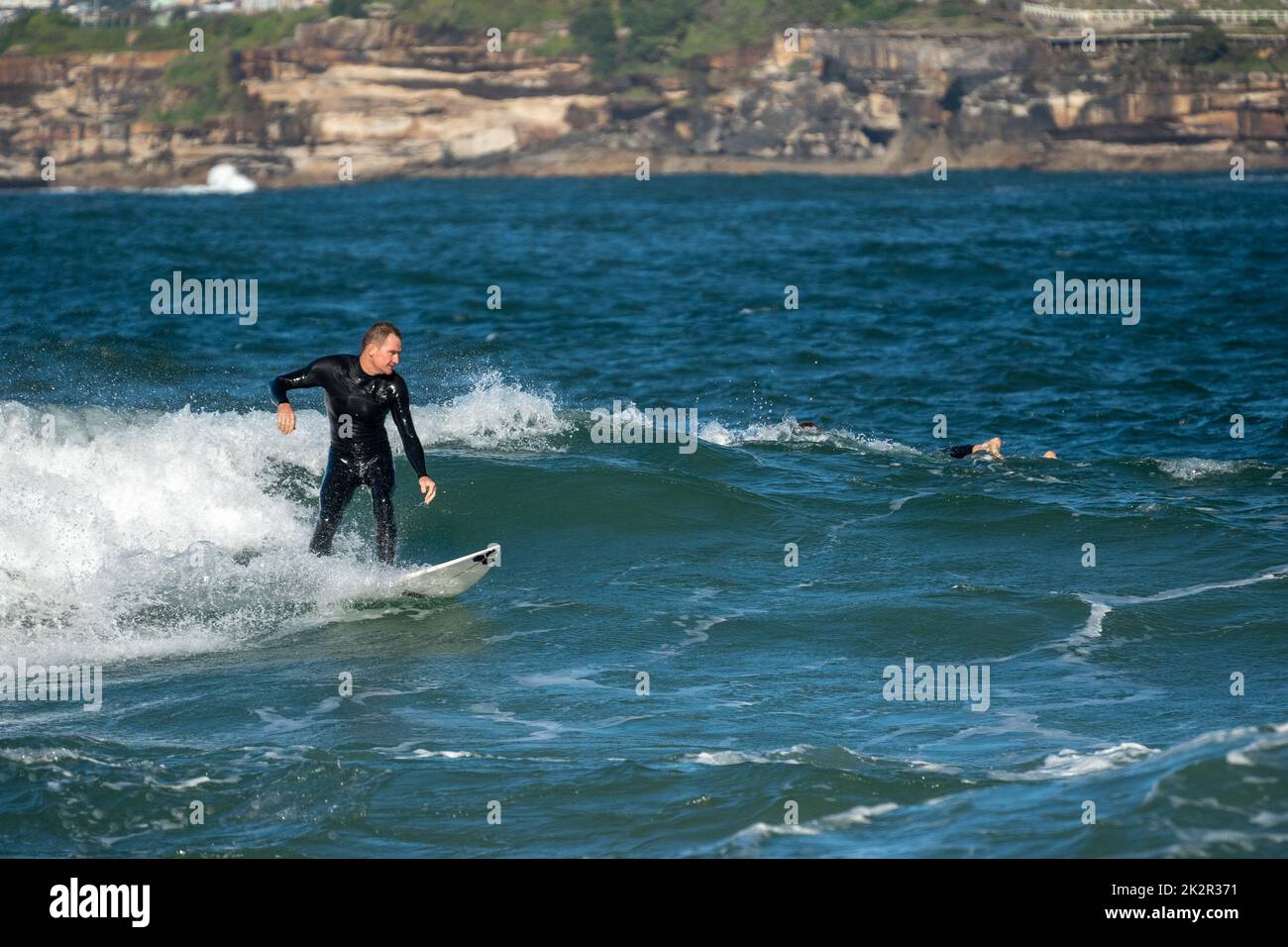 A surfer at the beach catching waves and scattering water around and a ...