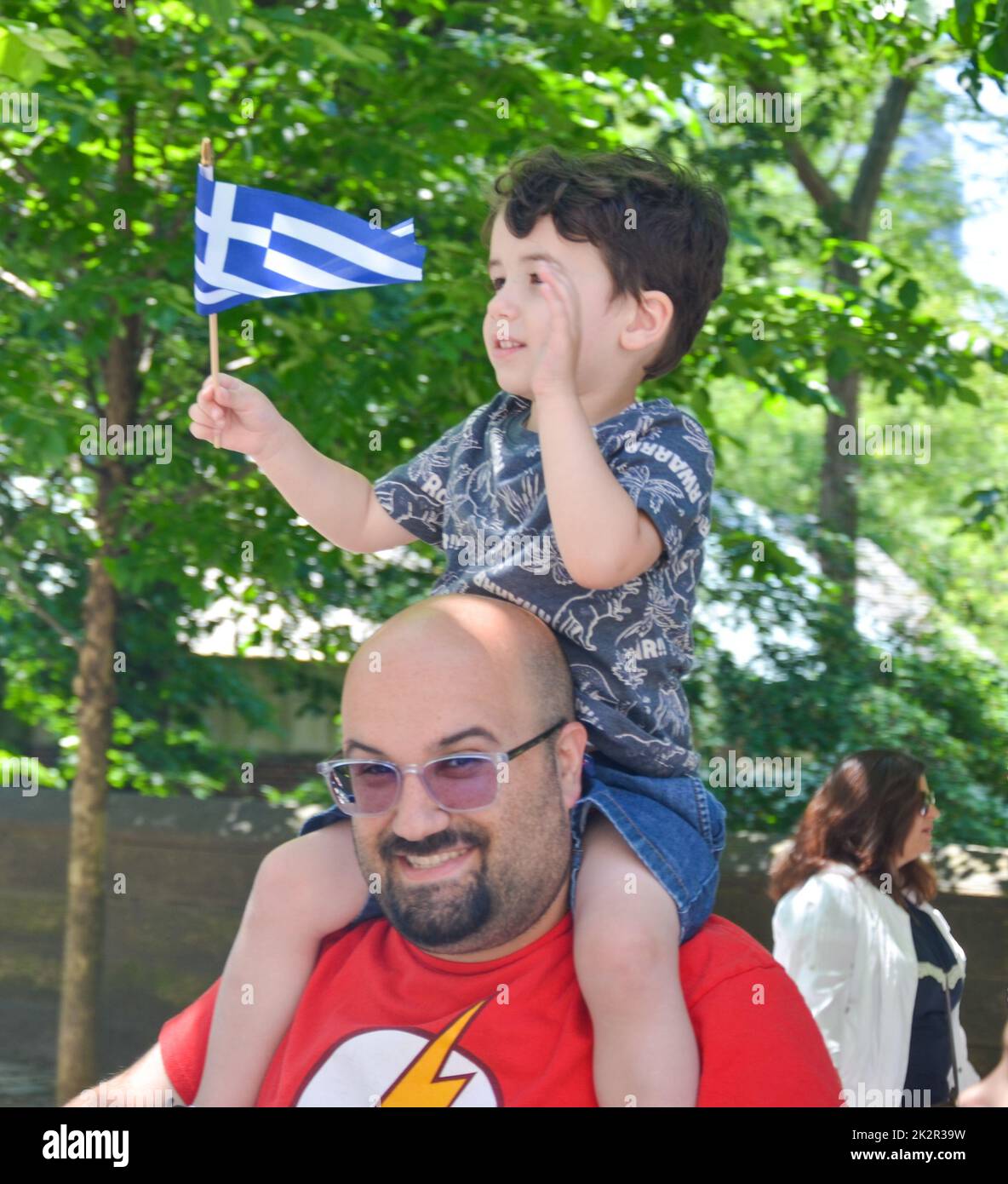 A vertical shot of a kid on his father's shoulders on the annual Greek ...