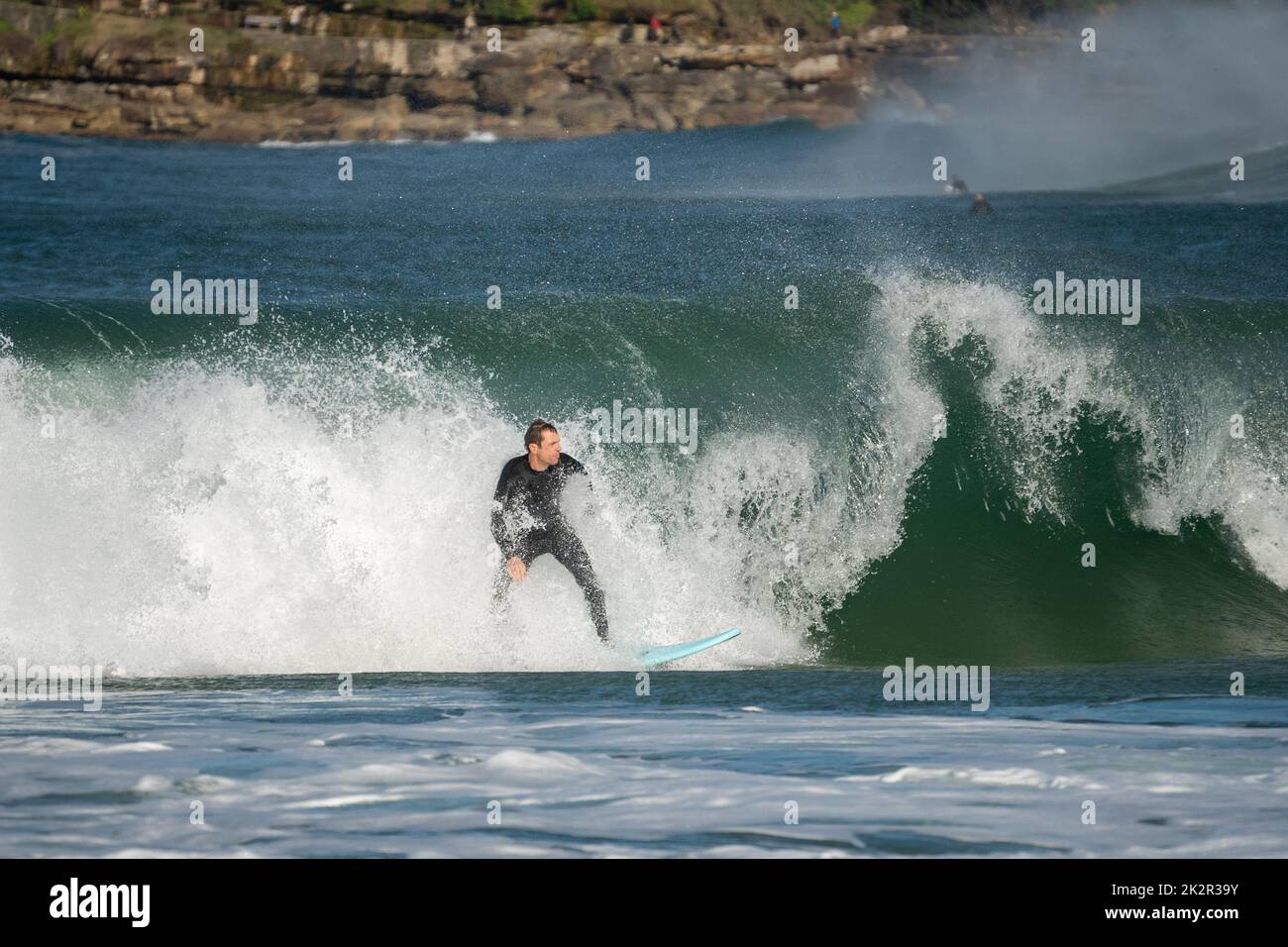 A surfer at the beach catching waves and scattering water around and a ...