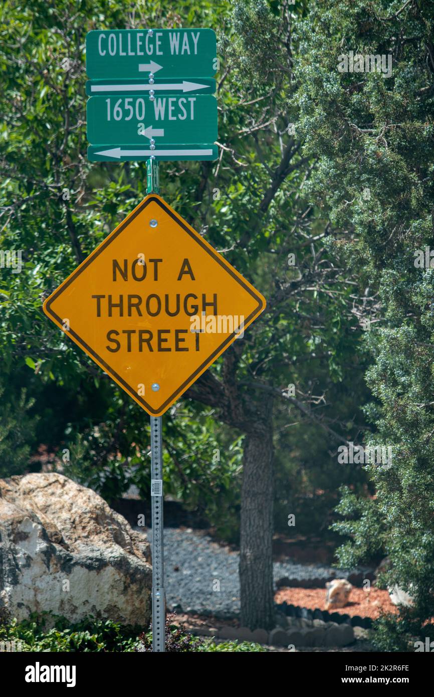 A vertical shot of a street sign pole with a yellow "not a through ...