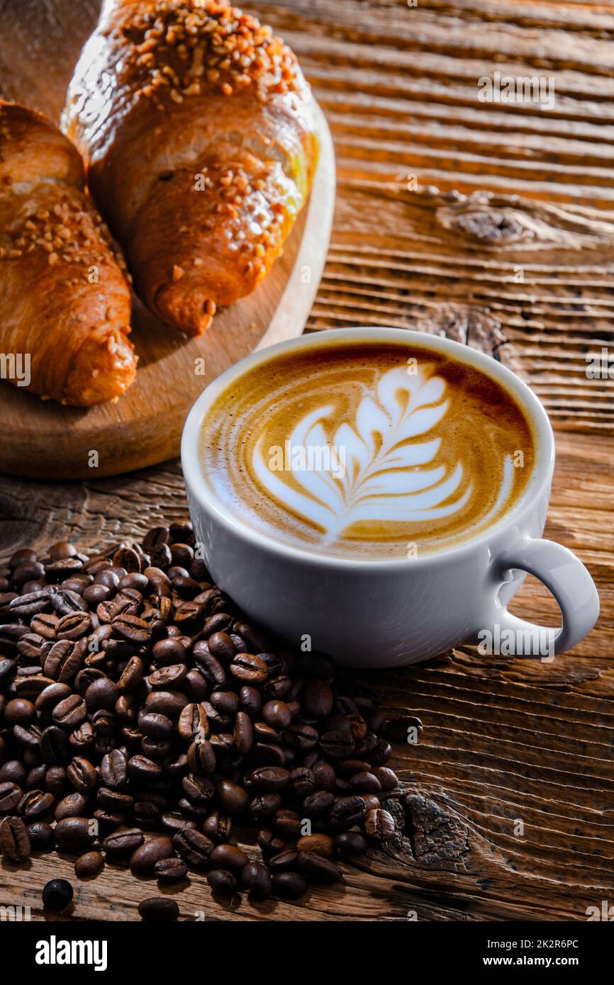 A cup of coffee and two croissants on an old wooden table Stock Photo ...