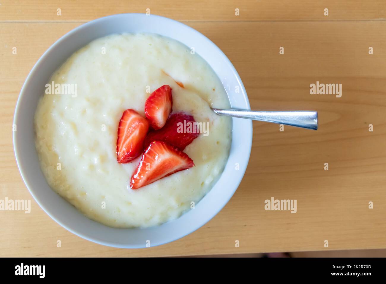 Many cut strawberries with rice pudding in bowl are ready to eat with ...
