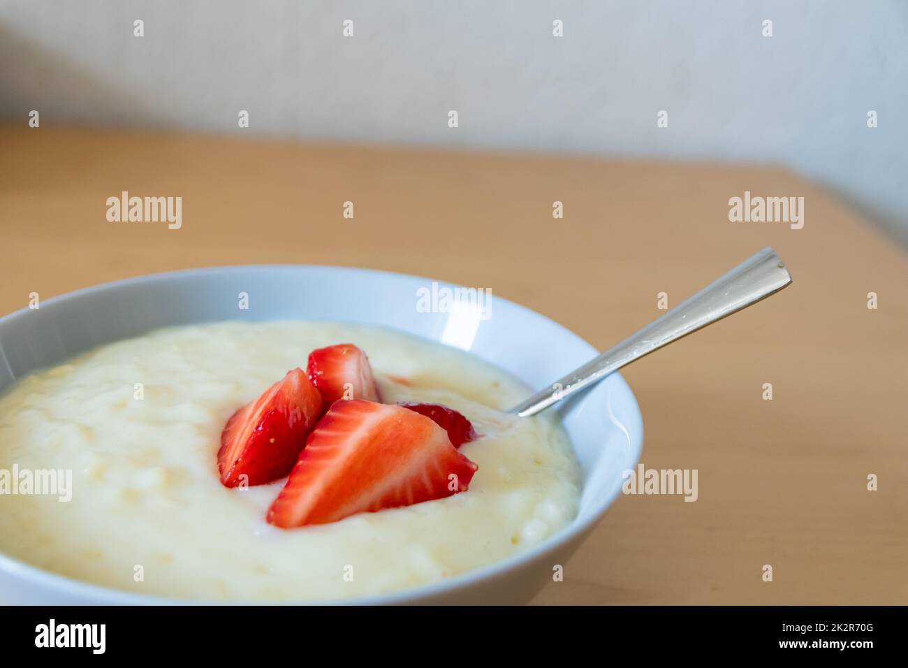 Many cut strawberries with rice pudding in bowl are ready to eat with ...