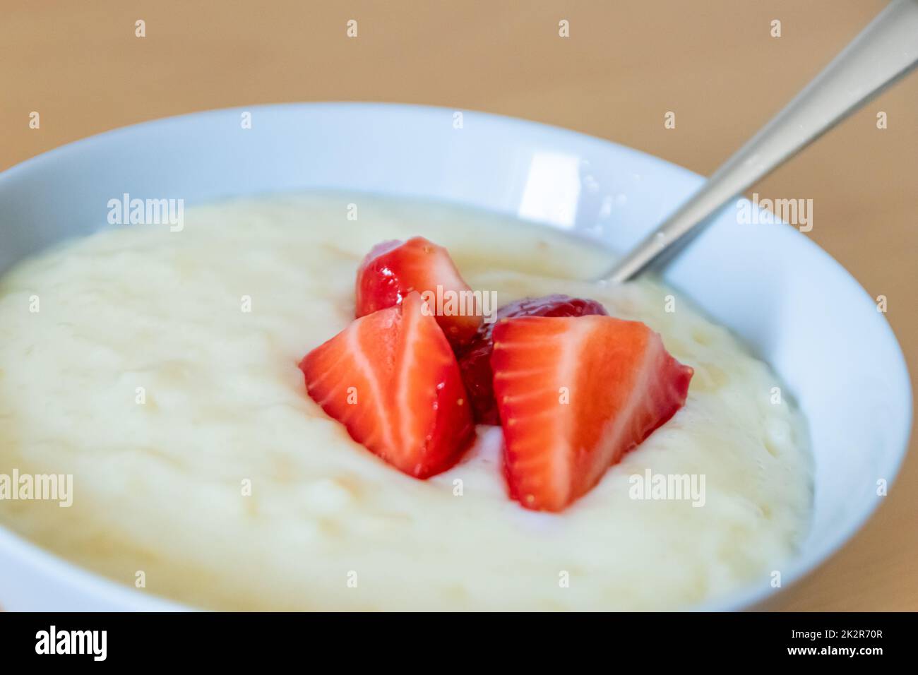 Many cut strawberries with rice pudding in bowl are ready to eat with ...