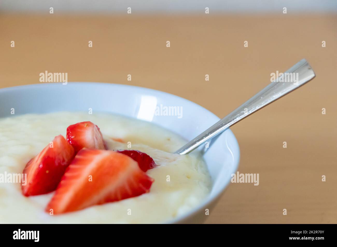 Many cut strawberries with rice pudding in bowl are ready to eat with ...