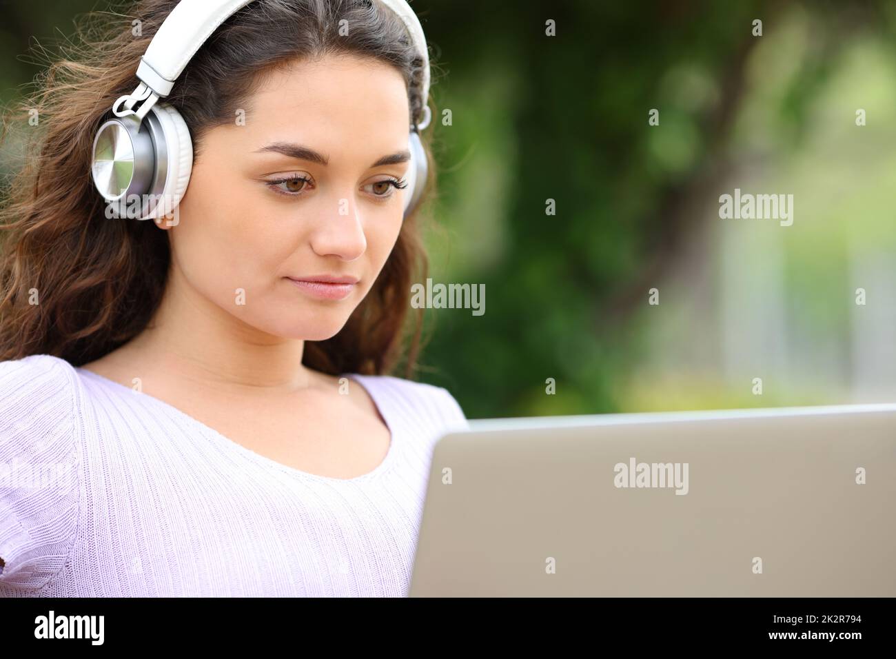 Woman with headphones watching media on laptop Stock Photo - Alamy