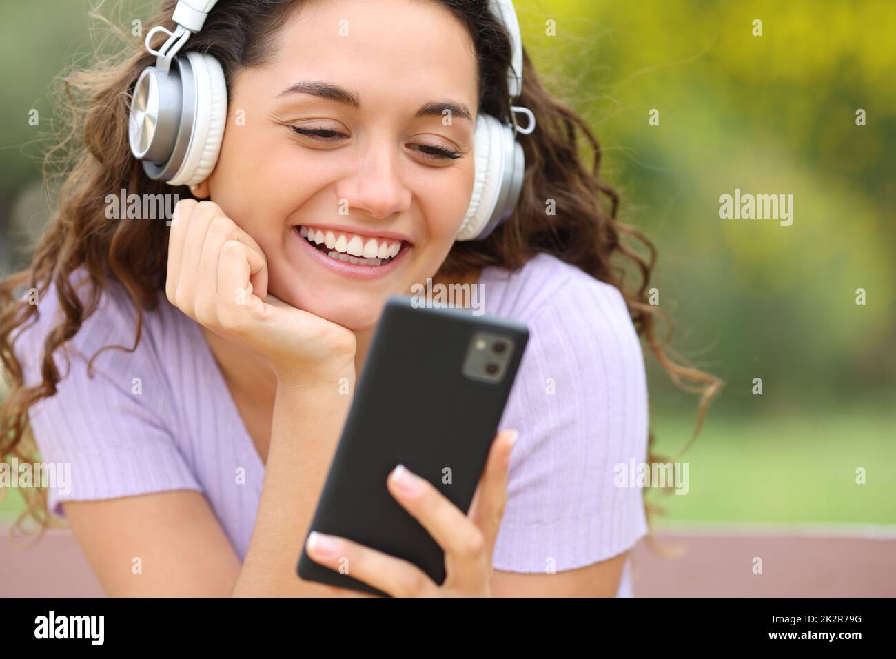 Happy woman listening and watching videos on phone Stock Photo - Alamy