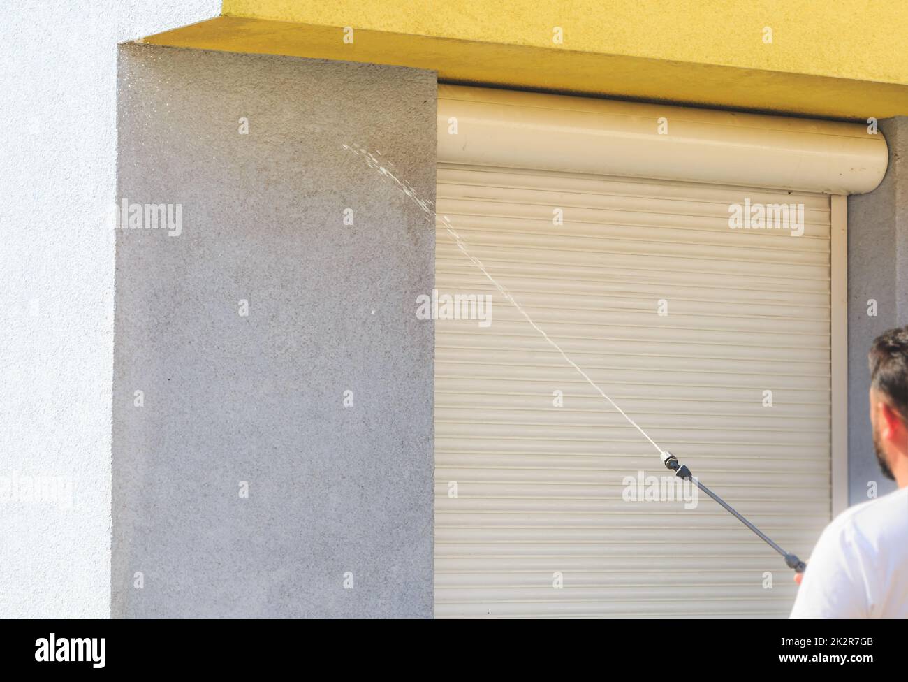 Applying cleaning supplies on dirty facade with high-pressure water ...