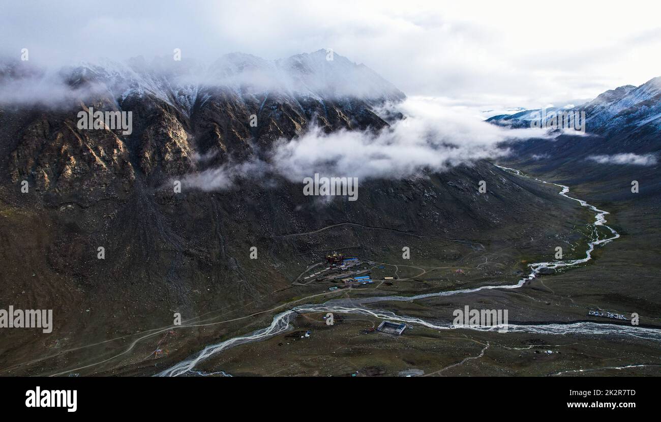 A drone view of a field with a flowing stream and a mountain covered ...