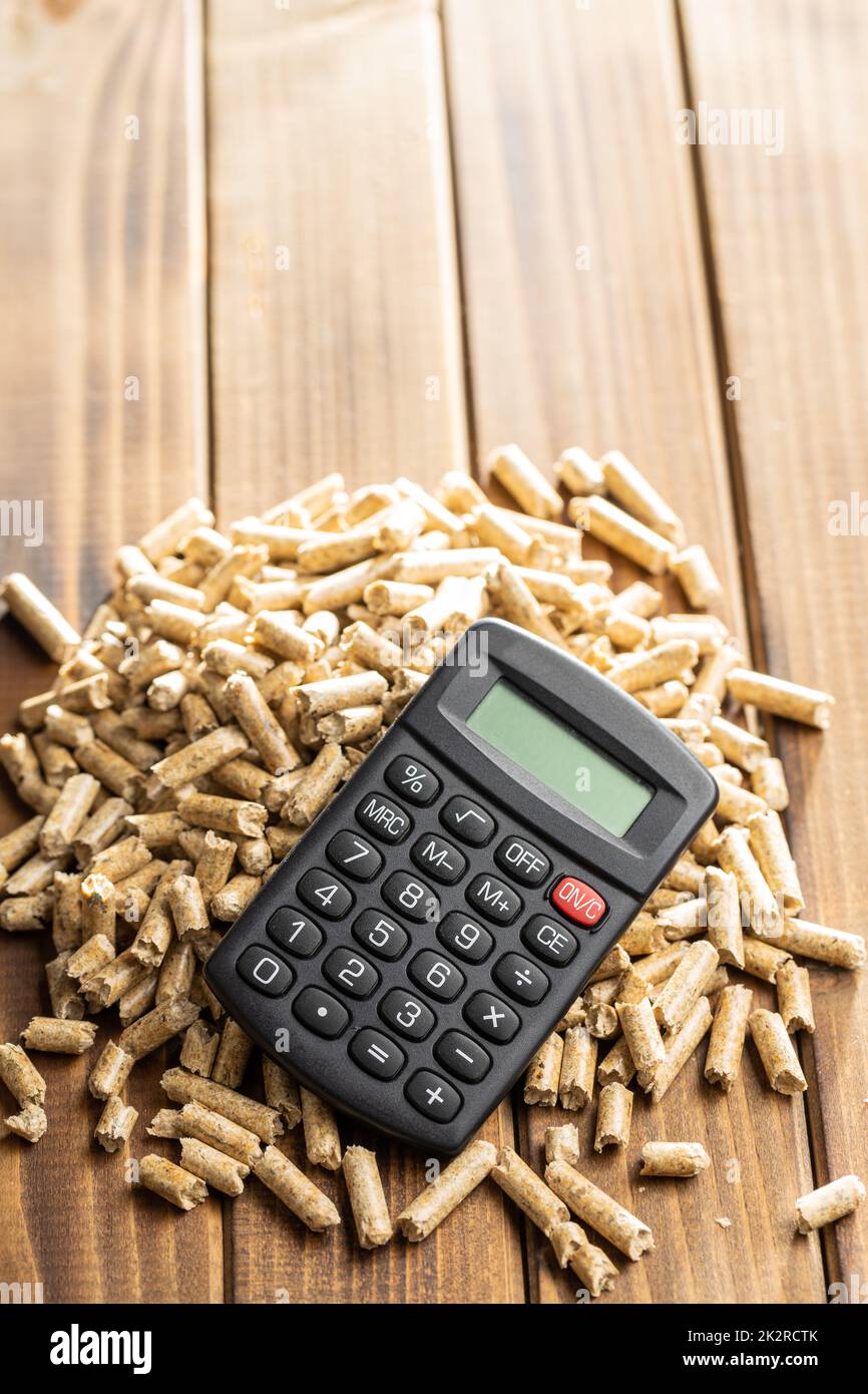 Wooden pellets and calculator, biofuel on wooden table. Ecologic fuel ...