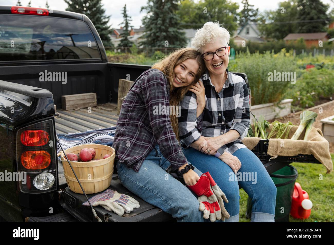 Portrait of mother and daughter sitting on rear of pickup truck Stock ...