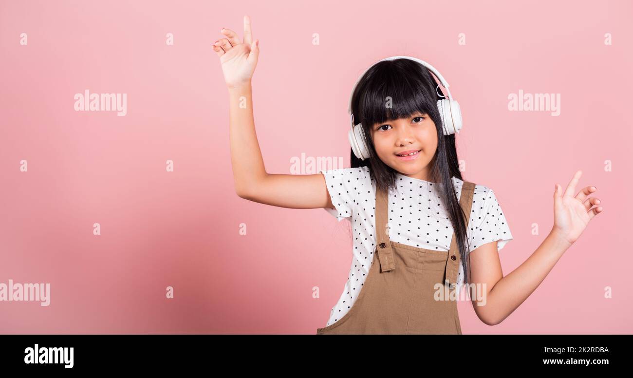 Asian little kid 10 years old smiling listening music wearing wireless ...