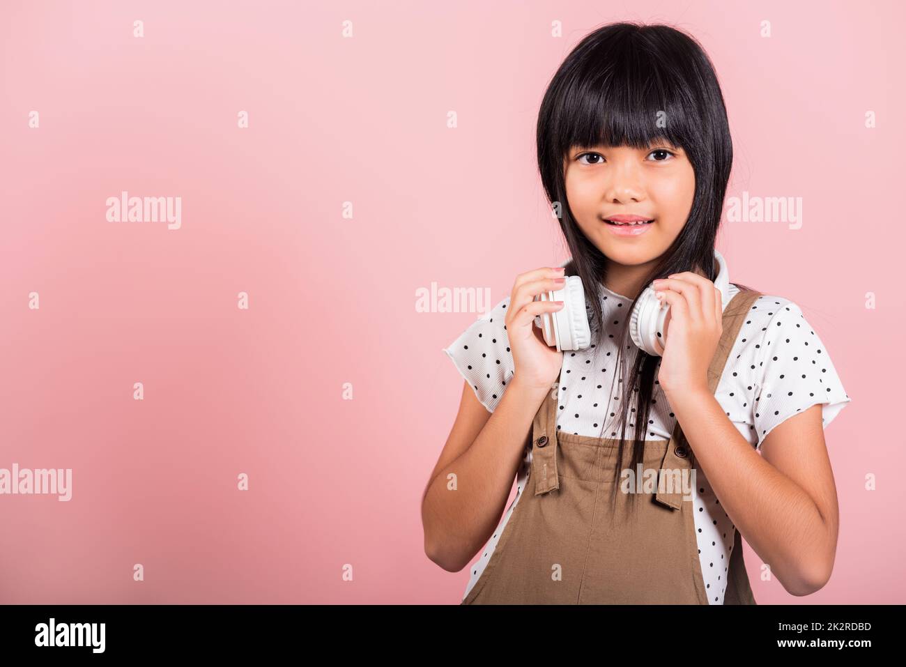 Asian little kid 10 years old smiling listening music wearing wireless ...