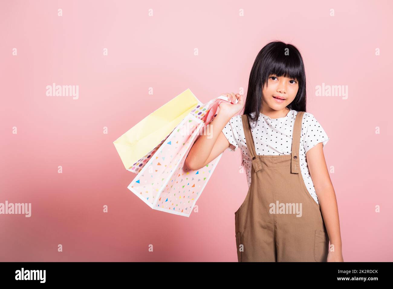 Asian little kid 10 years old smiling holding multicolor shopping bags ...