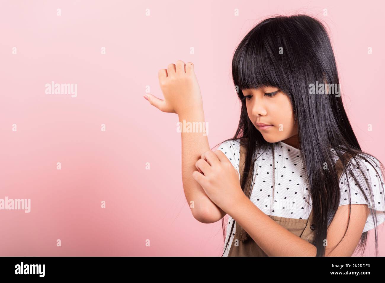 Asian little kid 10 years old scratching itch arm from a mosquito bite ...
