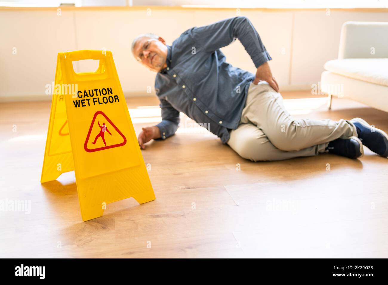 Man Falling On Wet Floor In Front Of Caution Sign Stock Photo - Alamy