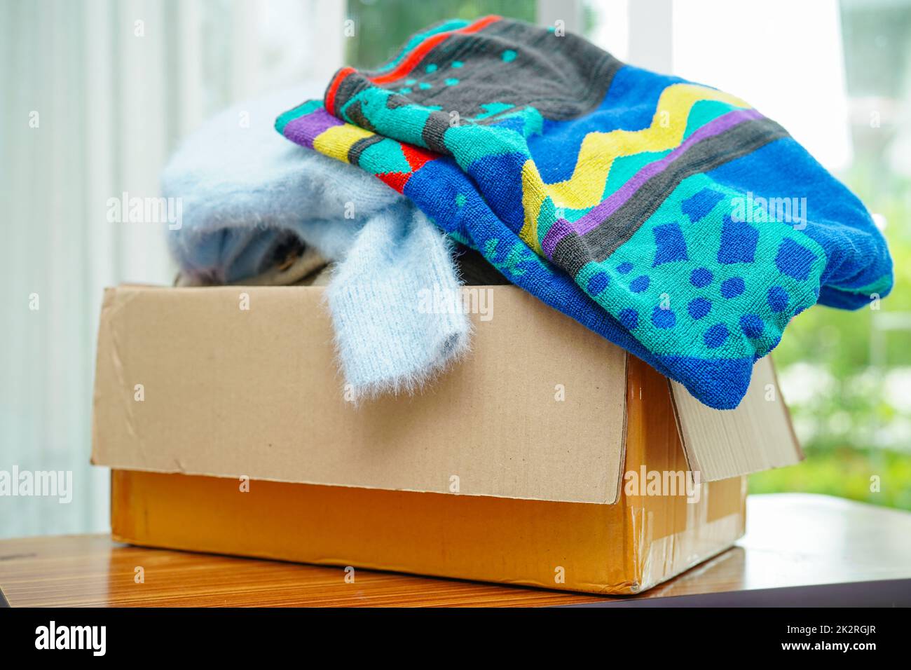 Clothes donations in cardboard box for volunteer Stock Photo - Alamy
