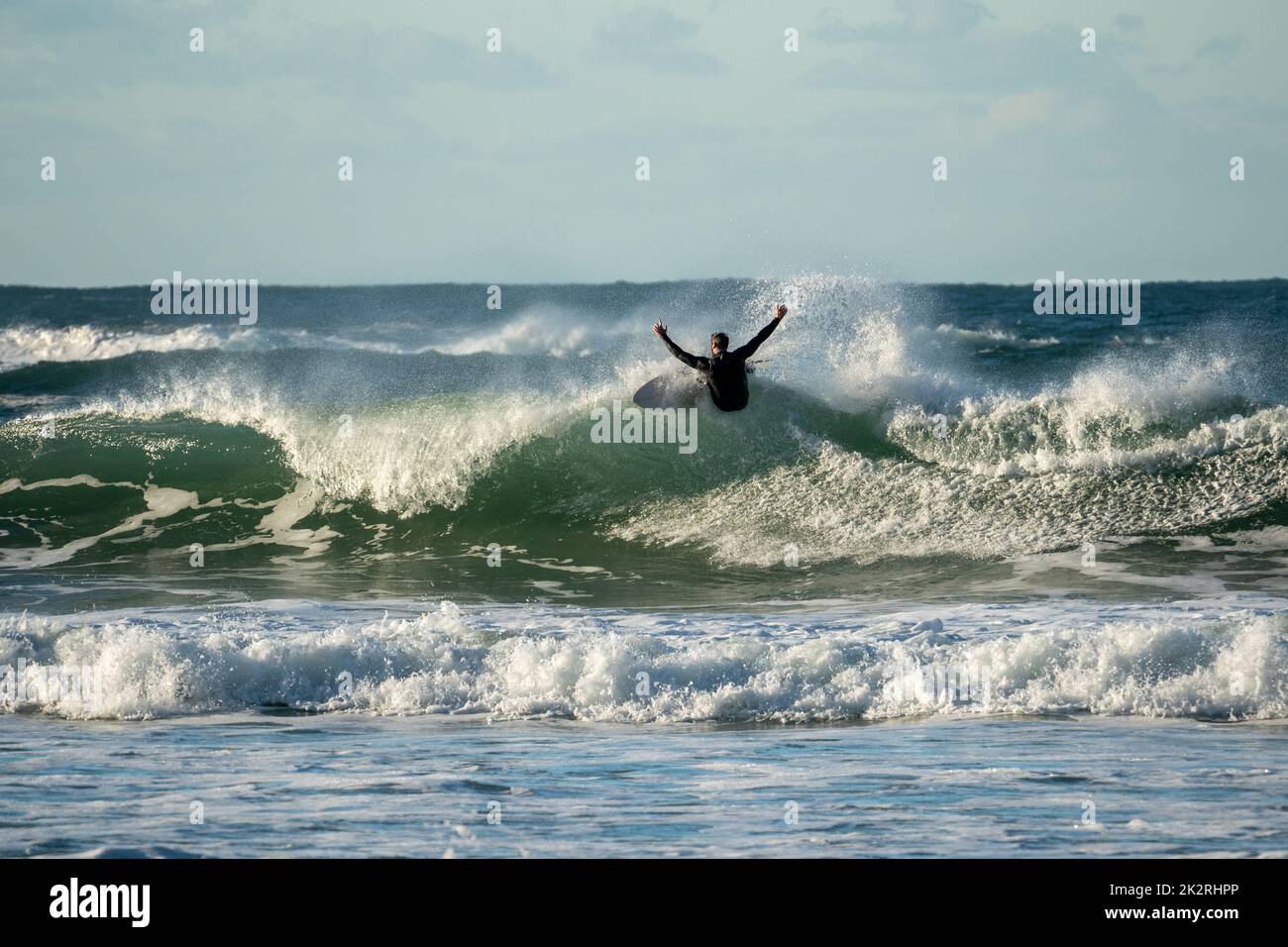 A young surfer catching waves before work on an early Friday morning at ...