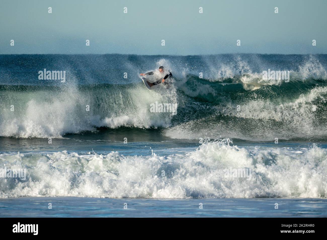 A young surfer catching waves before work on an early Friday morning at ...