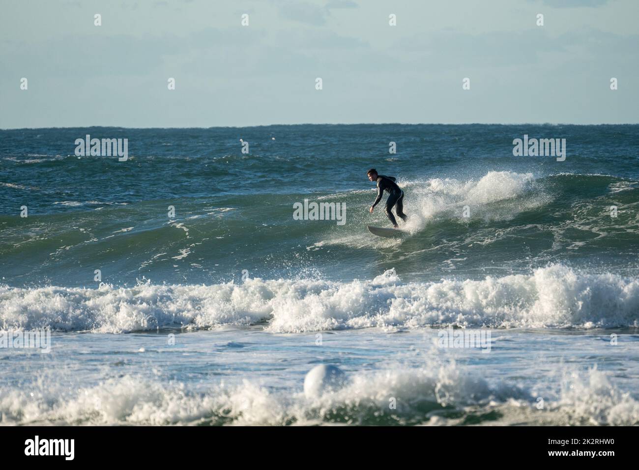 A young surfer catching waves before work on an early Friday morning at ...