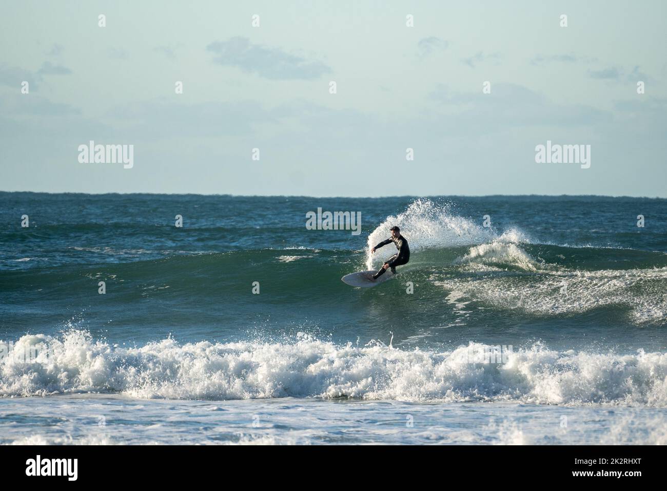 A young surfer catching waves before work on an early Friday morning at ...