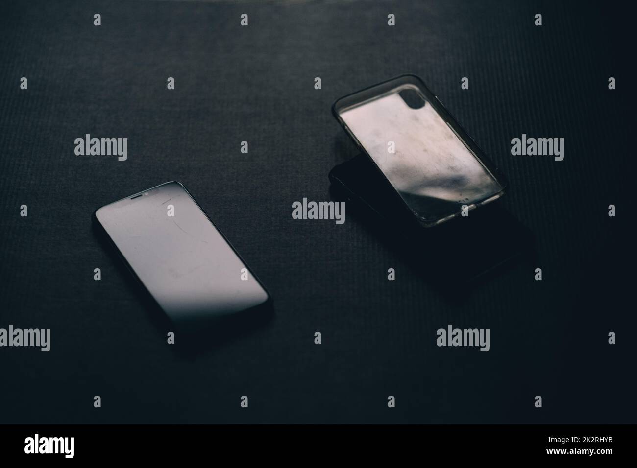 The two black phones with reflecting screens isolated on the dark ...