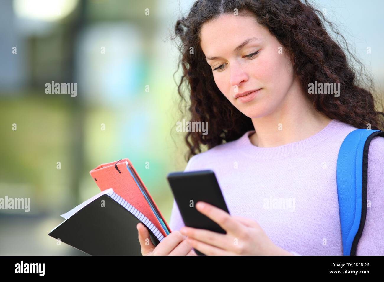 Serious student reading phone content in a campus Stock Photo - Alamy