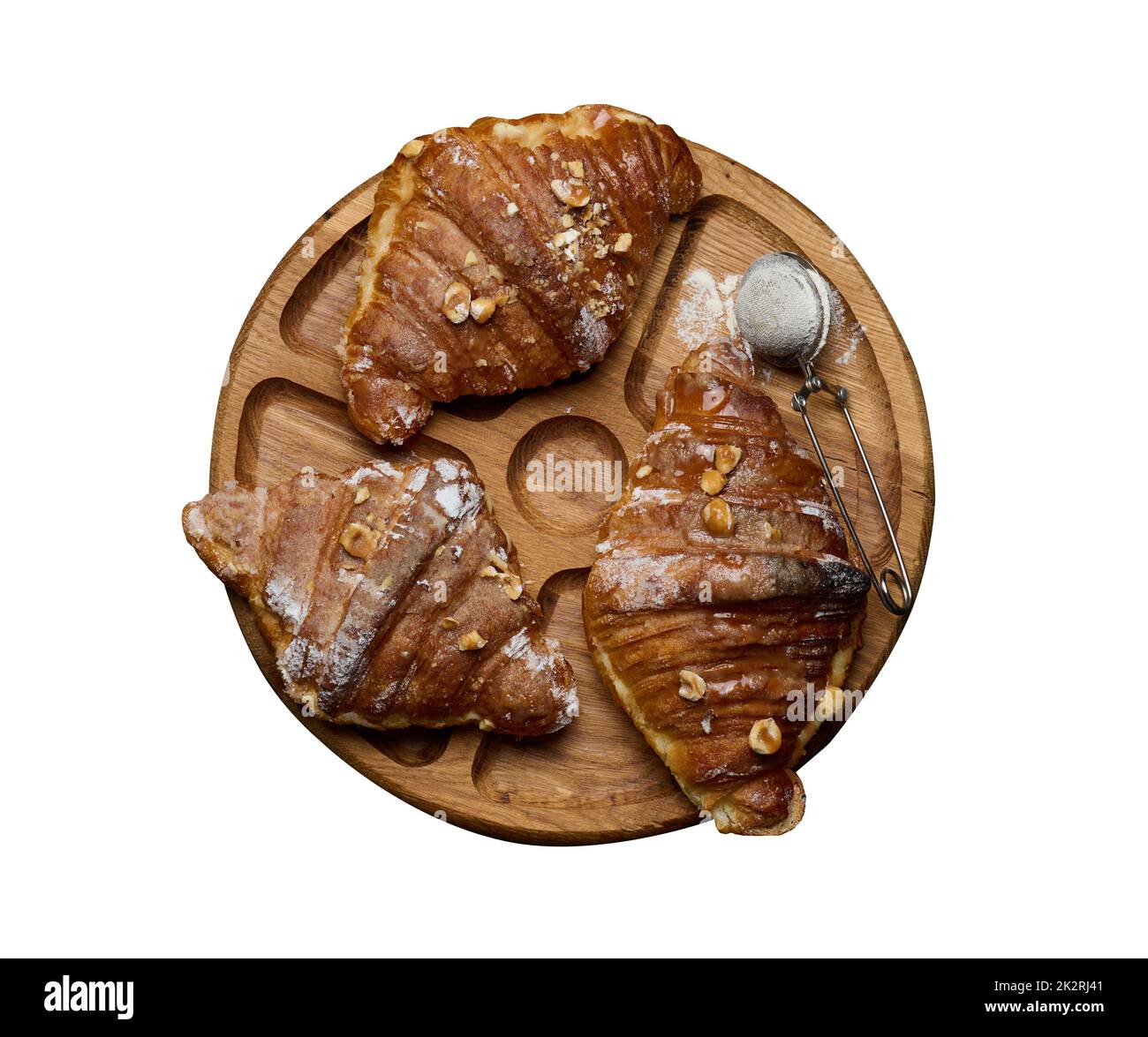 Baked croissant on a wooden board and sprinkled with powdered sugar ...