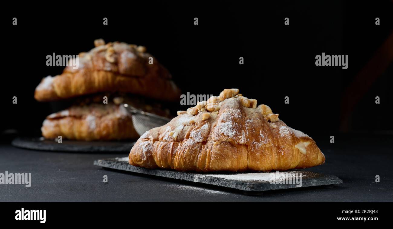 Baked croissant on a wooden board and sprinkled with powdered sugar ...