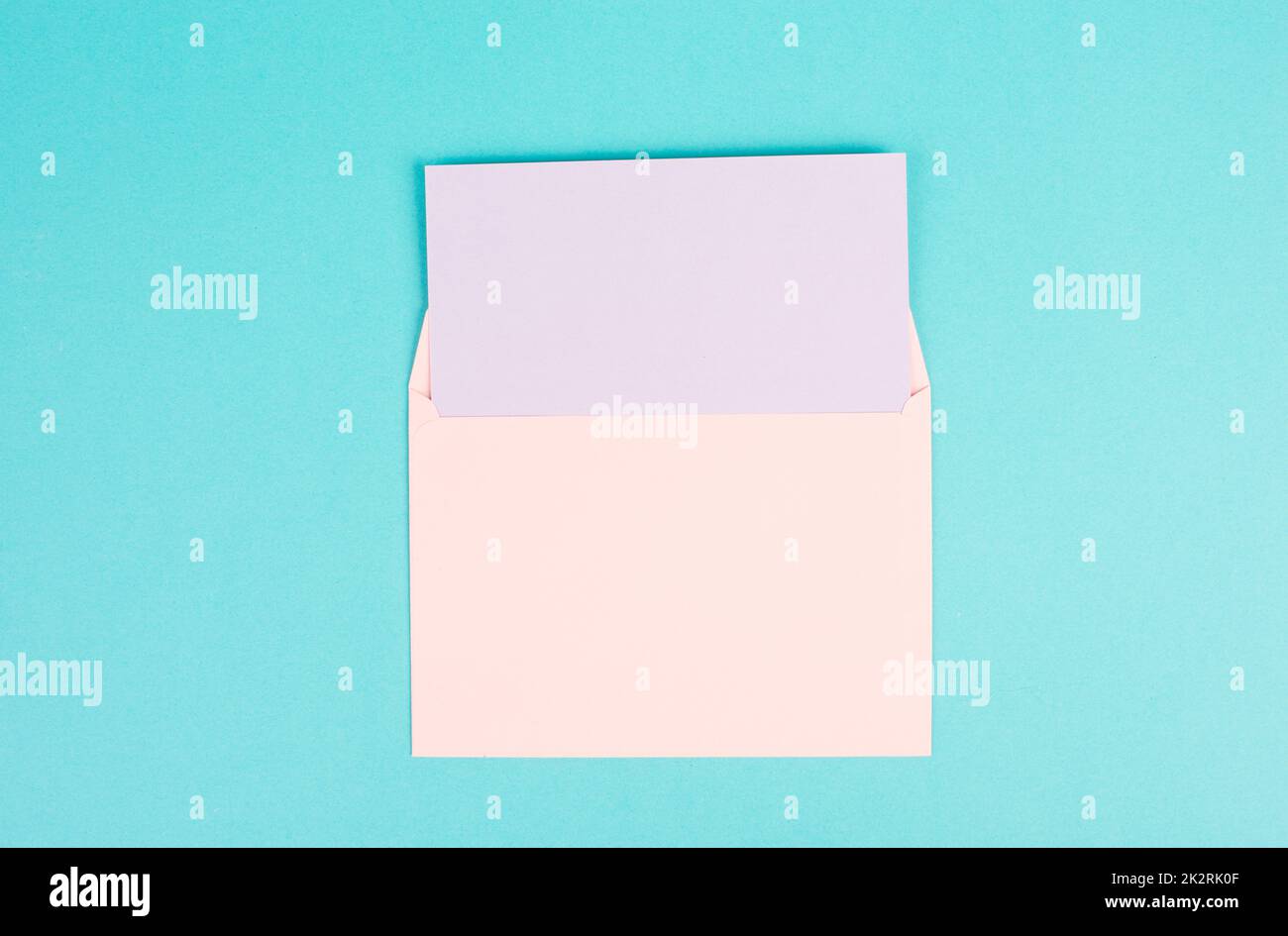 Pink colored envelope with an empty with paper on a turquoise ...